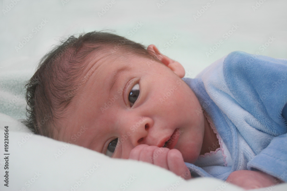 Bébé nouveau né qui louche allongé sur un lit Photos | Adobe Stock