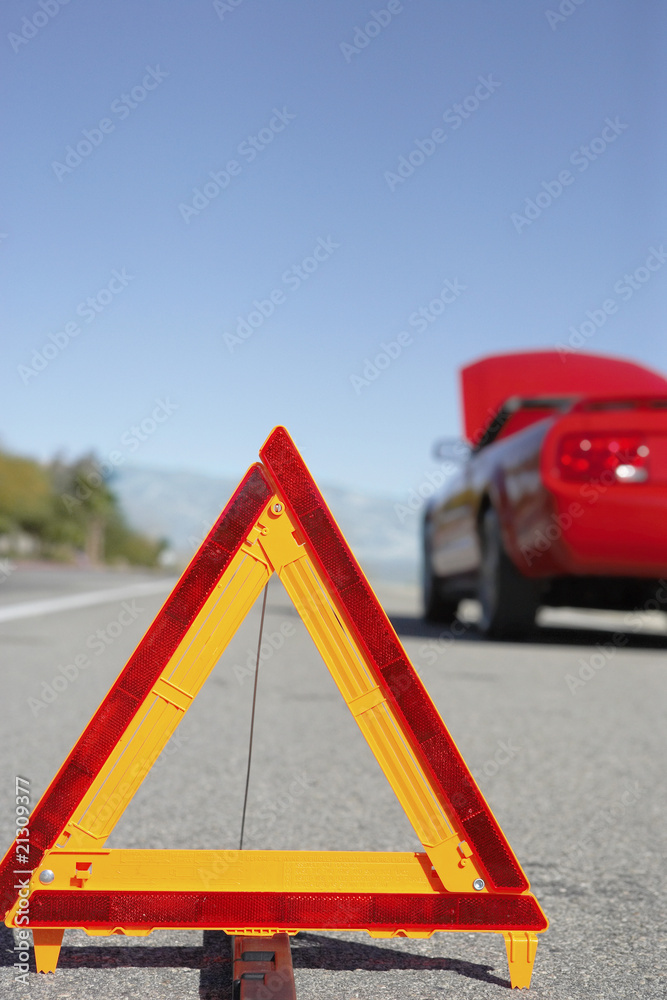 warning triangle in front of broken down red sports car at side of road ...