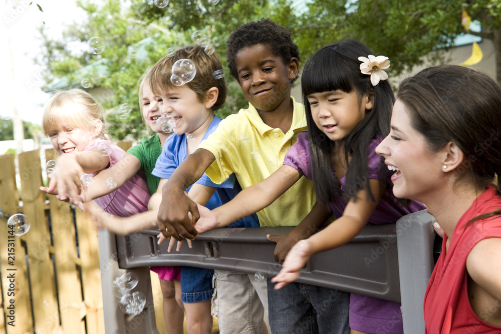 Preschool children playing on playground with teacher Stock Photo ...