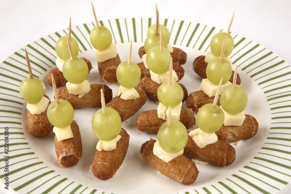 Plate of appetizers, mini pork sausages, with cheese and grapes Stock ...