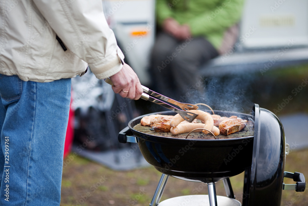 mann steht auf dem campingplatz am grill Stock Photo | Adobe Stock