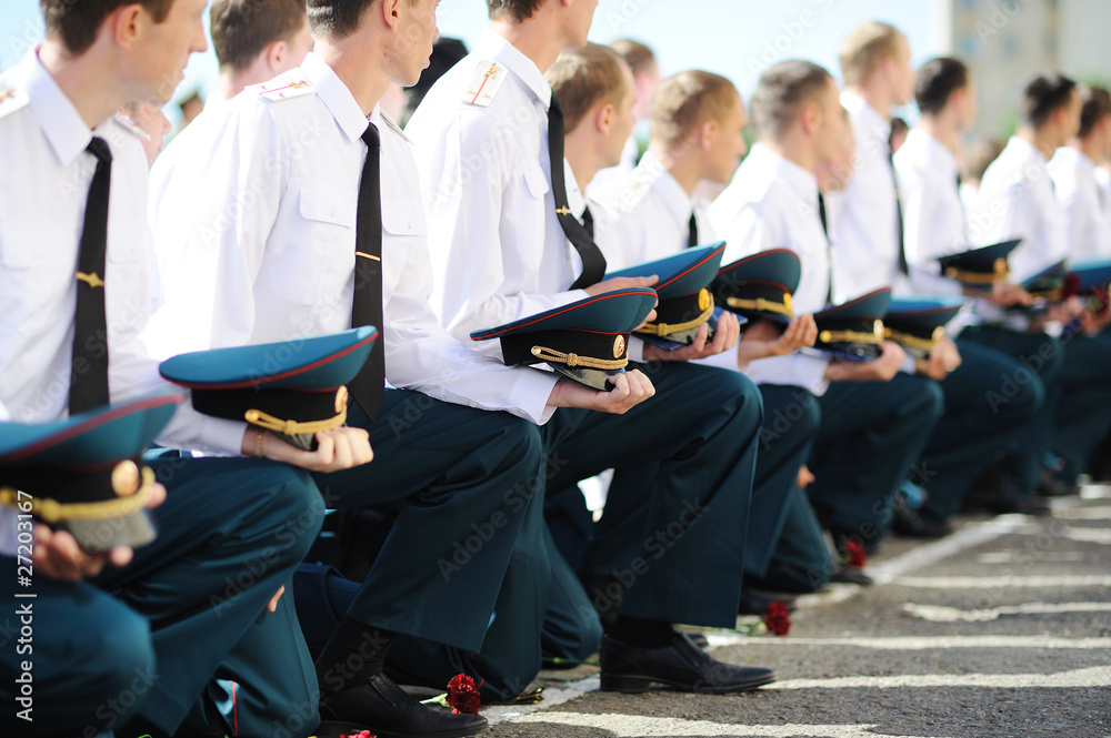 cadets graduates standing on their knees salute in the ranks. Victory ...