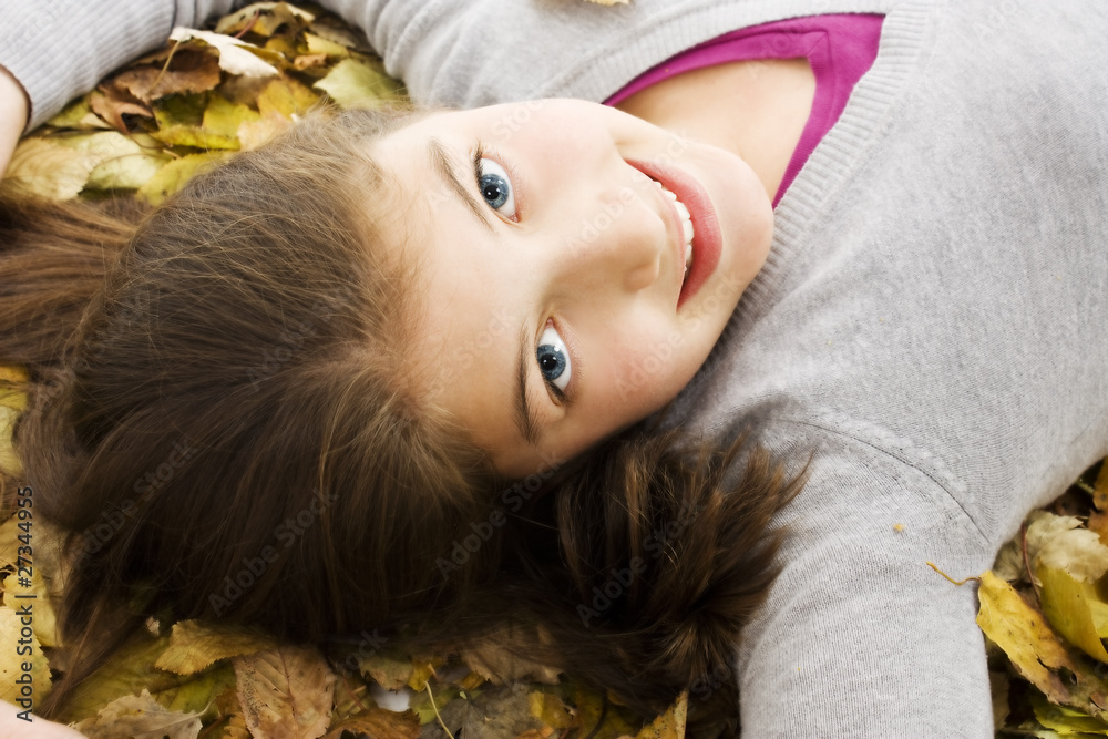 Portrait of teenage girl lying down with leaves around. Stock Photo ...