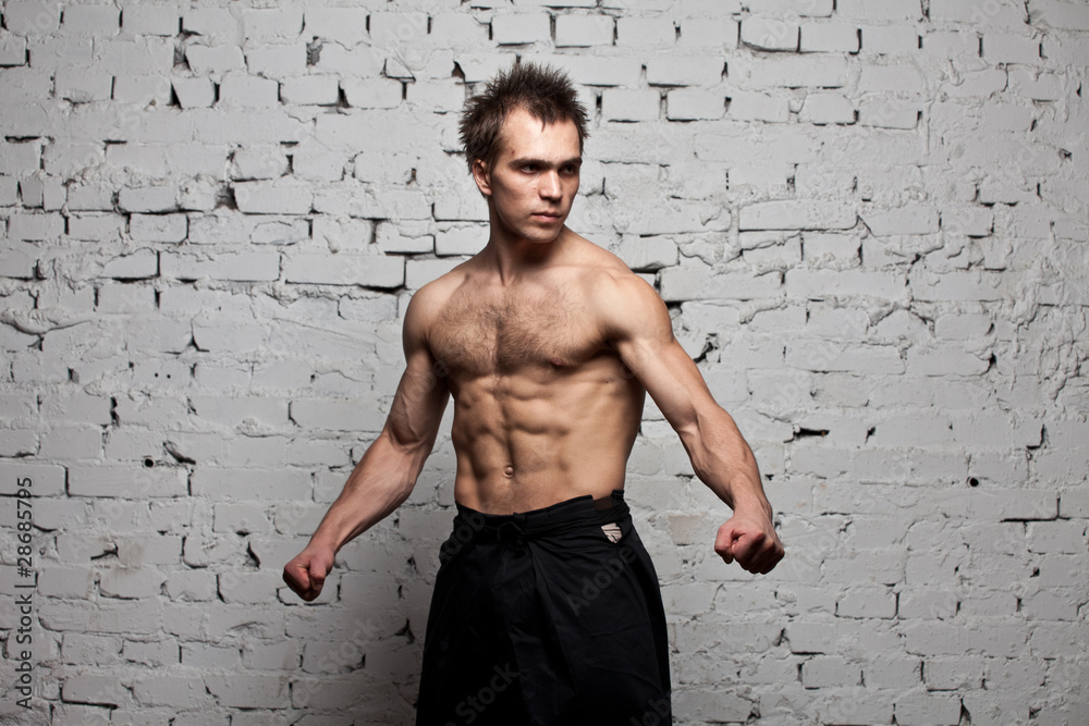 Strong muscular man stay at white brick wall Stock Photo | Adobe Stock