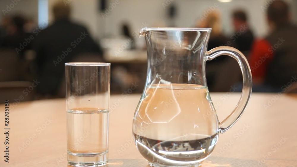 Cup and pitcher filled with water stand on table Stock Video | Adobe Stock