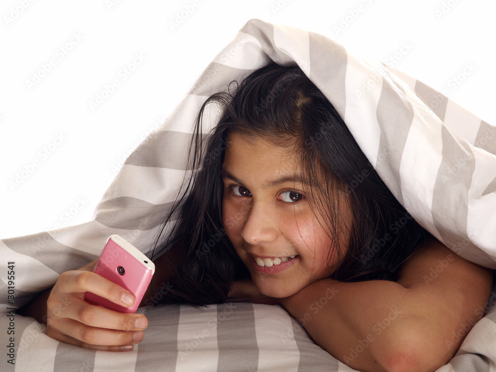 girl hiding under bed sheets with mobile phone Stock Photo | Adobe Stock