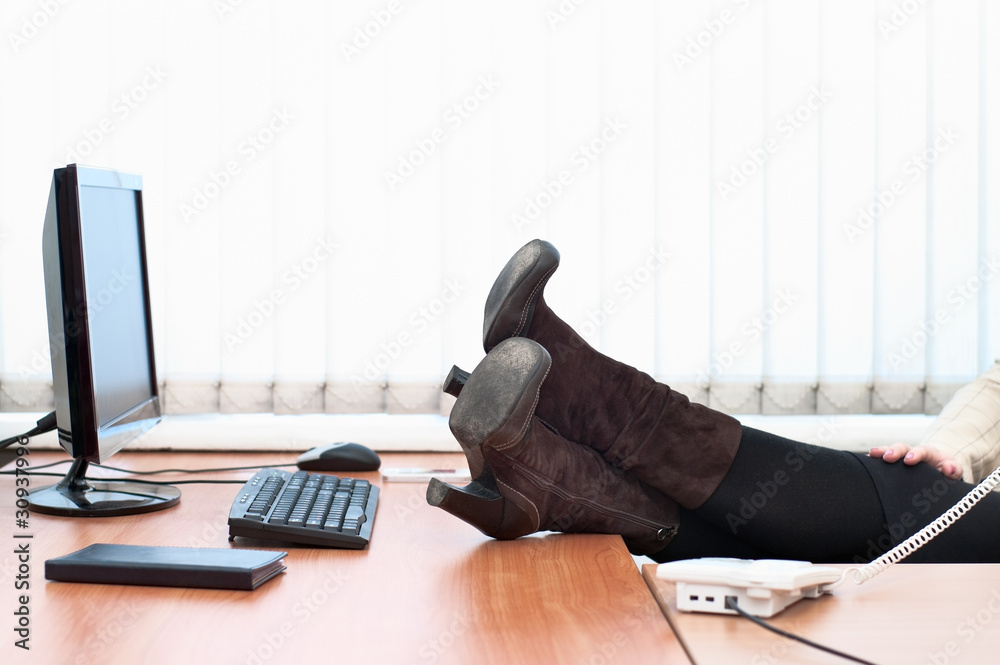Women's feet in boots lies on the desktop Stock Photo | Adobe Stock