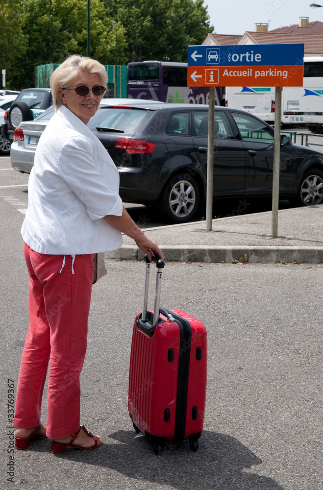 femme retraitée qui voyage avec une valise rouge Stock Photo | Adobe Stock