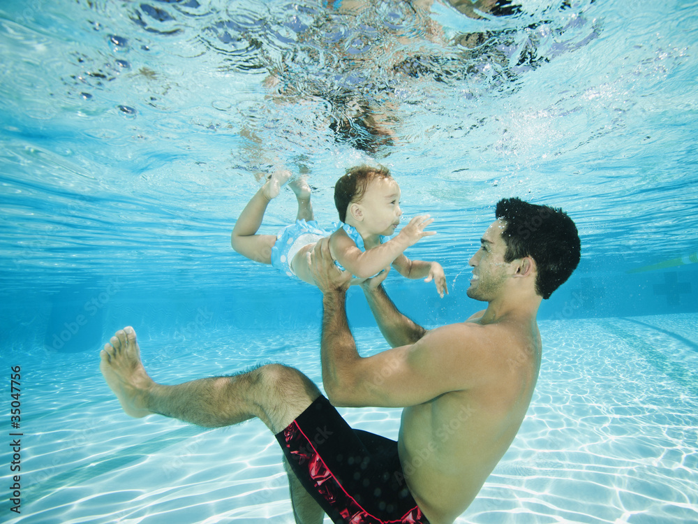 Father swimming underwater with daughter in swimming pool Stock Photo ...