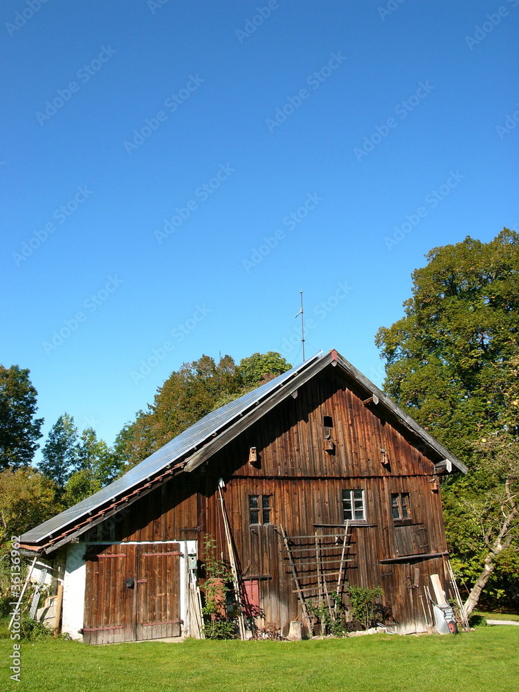 Schöne alte Scheune aus braunem Holz im Sommer vor blauem Himmel im ...
