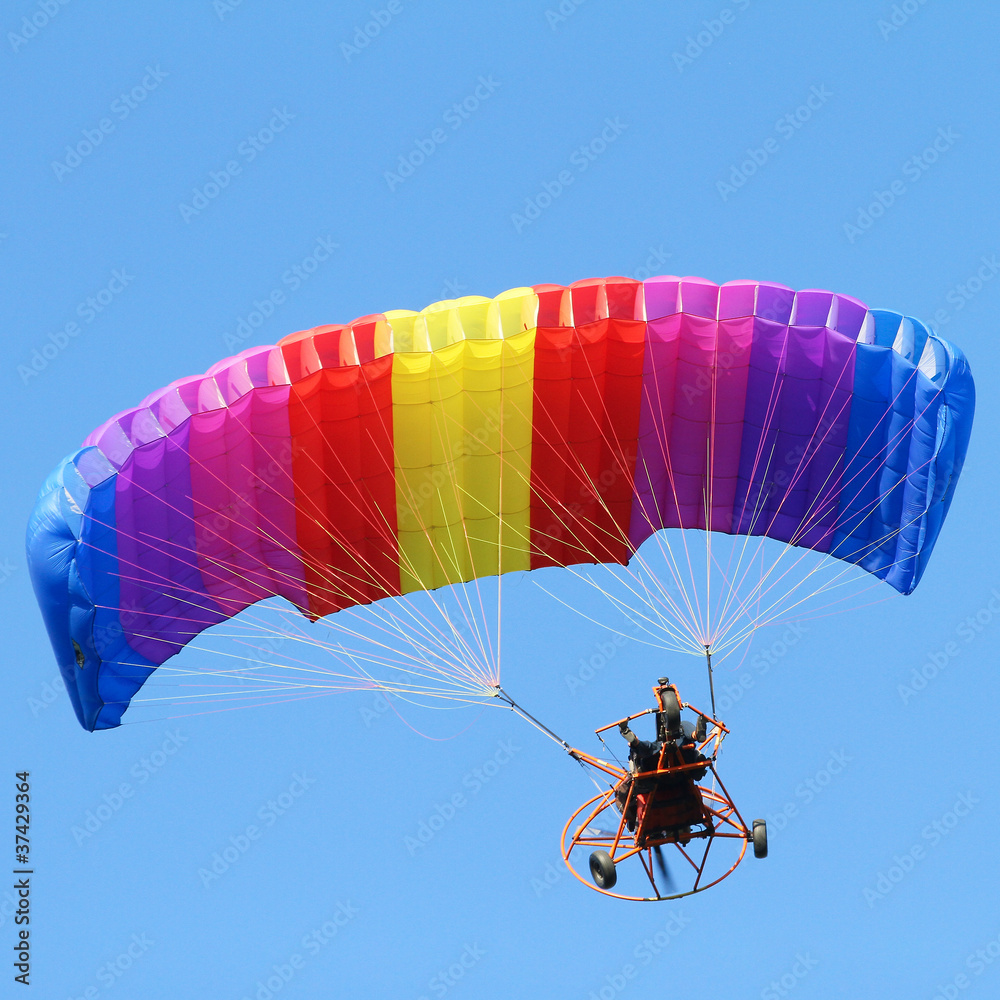 Colorful paraglider on blue bright sky Stock Photo | Adobe Stock