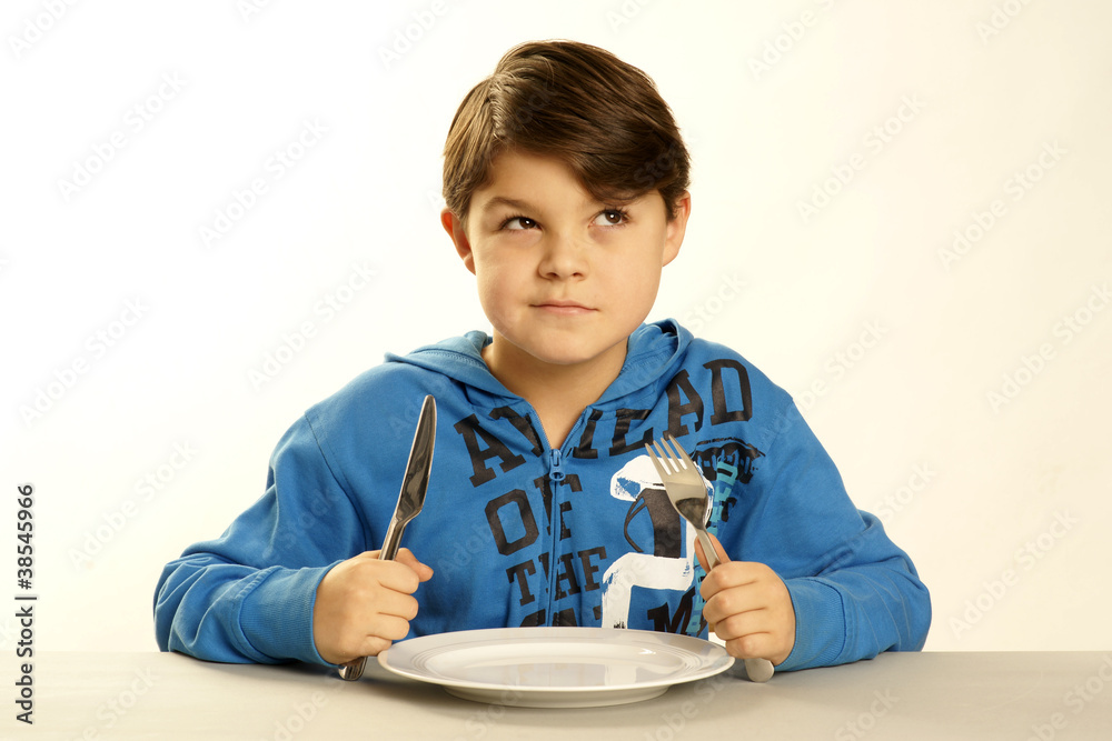 Kleiner Junge sitzt vor einem leeren Teller Stock Photo | Adobe Stock