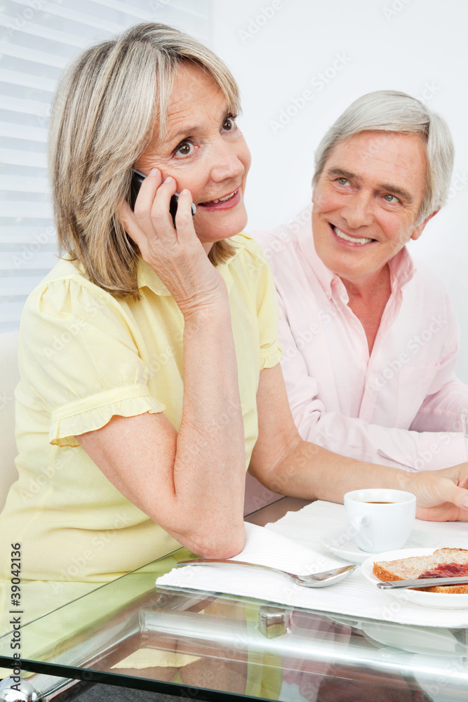 Seniorin mit Handy am Tisch Stock Photo | Adobe Stock