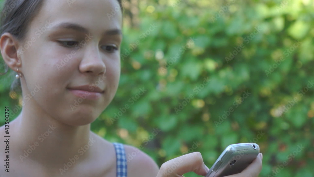Teenage girl dialing number on smartphone in park outdoors Stock Video ...