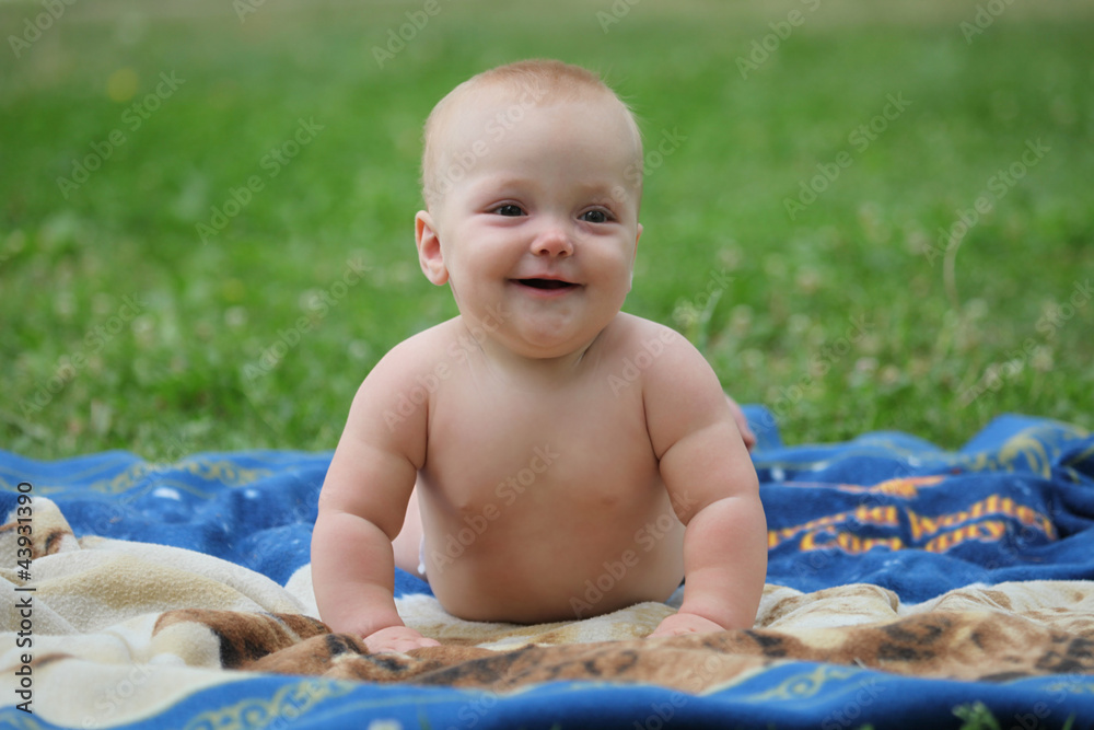 Smiling cheerful baby lying on lawn. Stock Photo | Adobe Stock