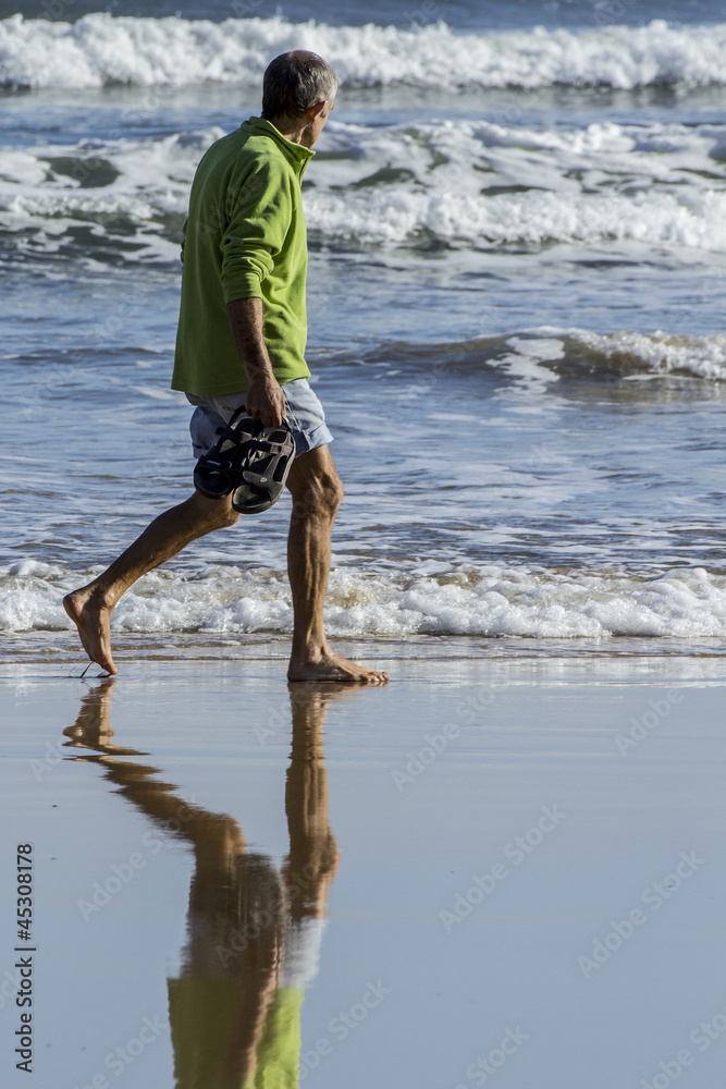 Hombre caminando por la playa foto de Stock | Adobe Stock