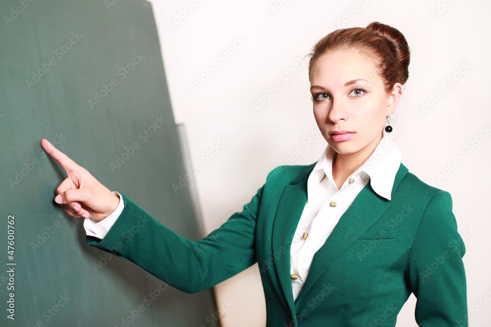 Hübsche Lehrerin zeigt auf eine Tafel Stock-Foto | Adobe Stock