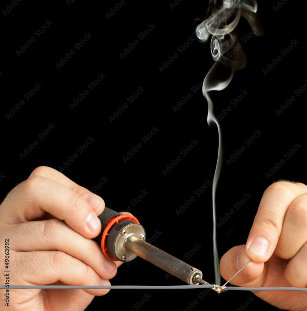 Soldering Tech soldering a gray wire on a pure black background. Stock ...