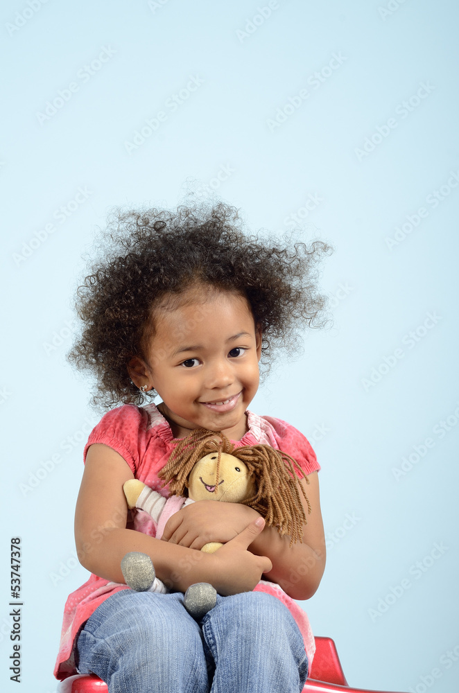 Little girl sitting and hugging a rag doll Stock Photo | Adobe Stock