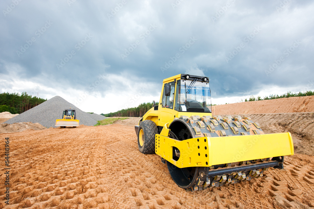 Soil compactor and bulldozer during road construction works Stock Photo ...