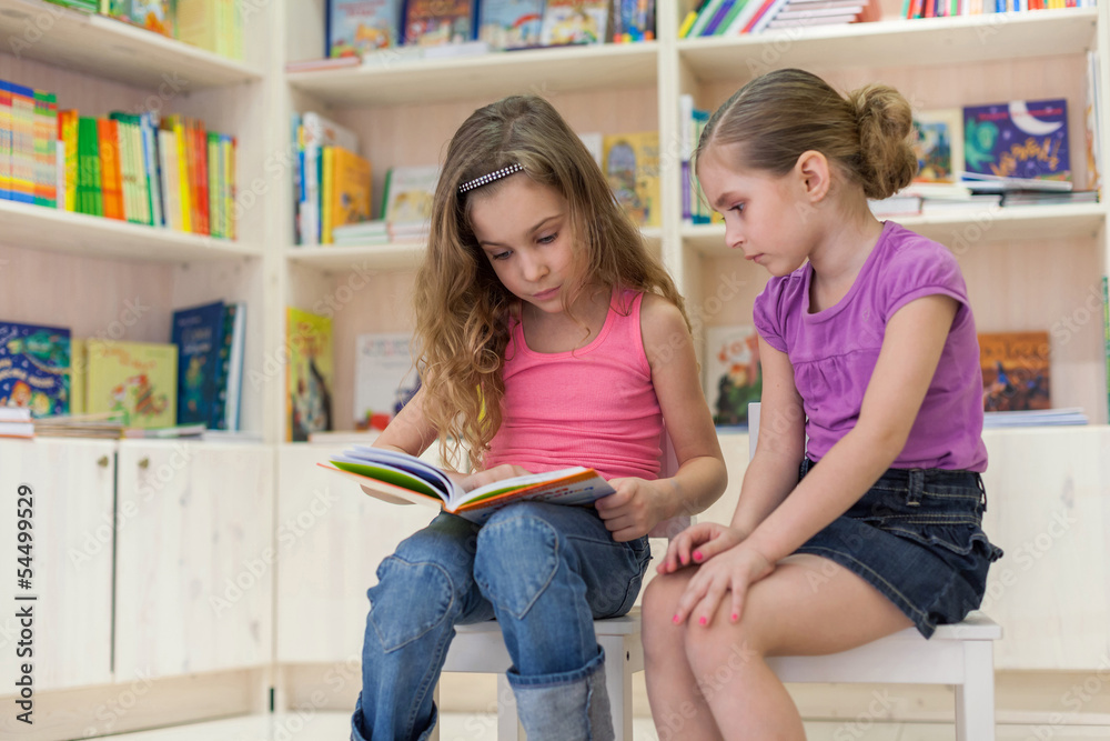 Two girls are concentrated in library reading a book Stock Photo ...