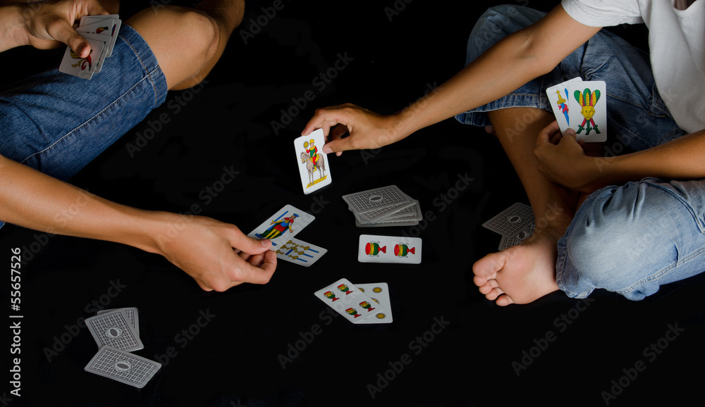 Two boys playing cards on black floor at night foto de Stock | Adobe Stock