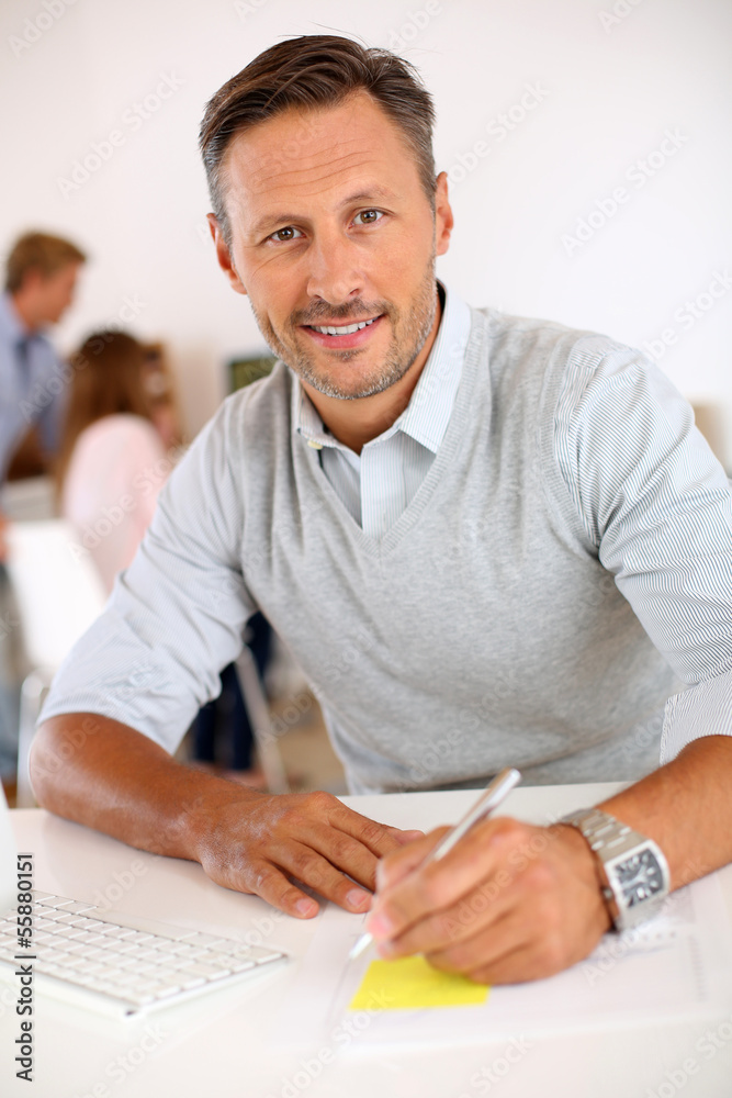 Cheerful man sitting in office and working on desktop Stock Photo ...
