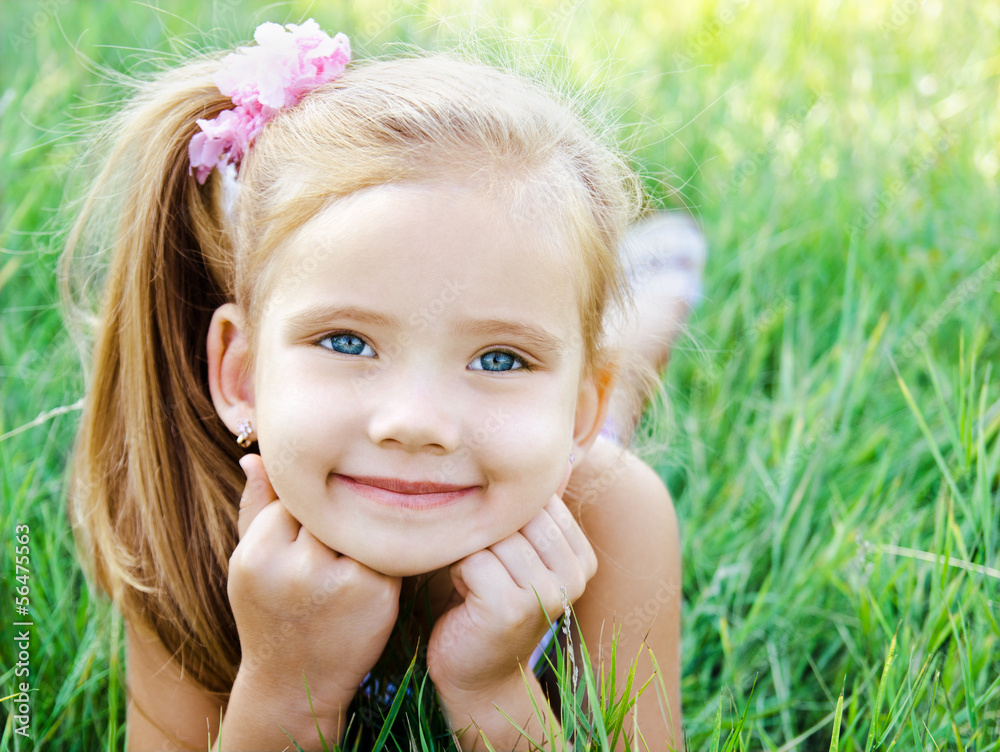 Cute smiling little girl lying in grass on the meadow Stock Photo ...