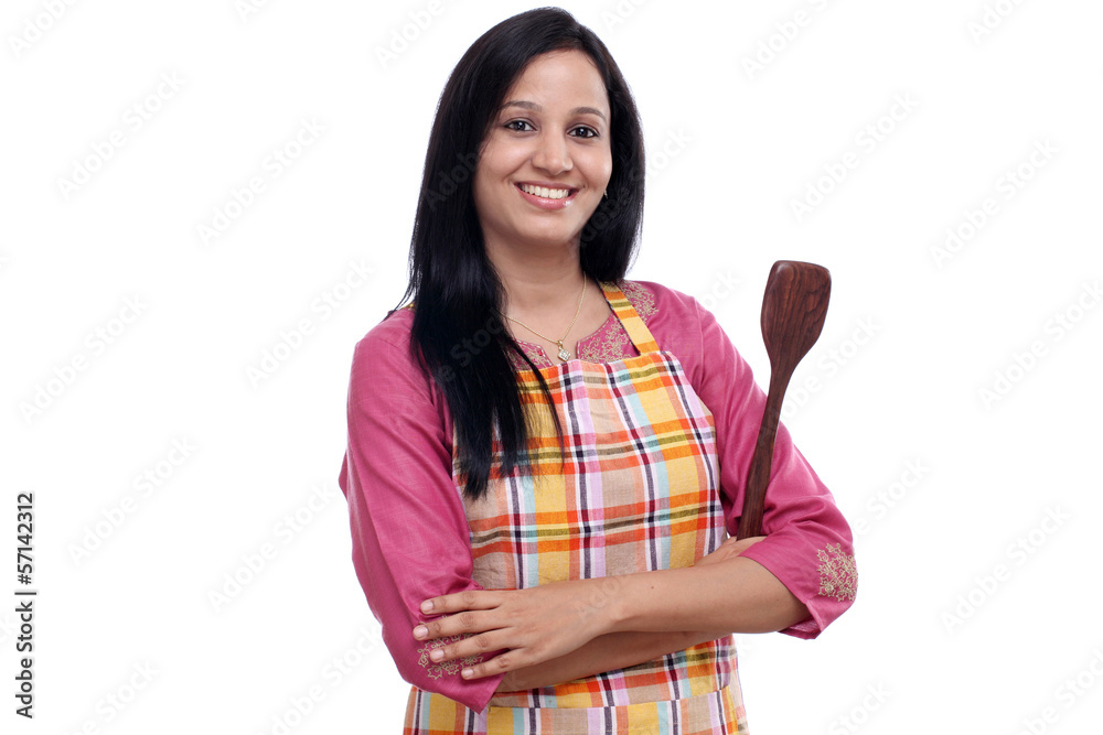 Young Indian woman holding kitchen utensil against white Stock Photo ...