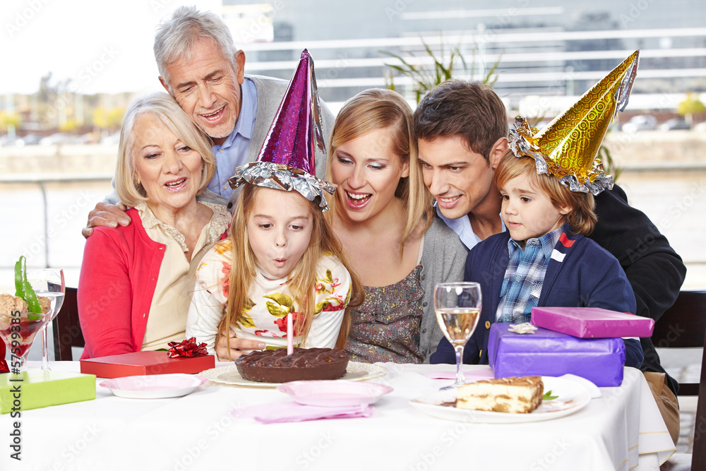 Girl blowing out candles at birthday party Stock Photo | Adobe Stock