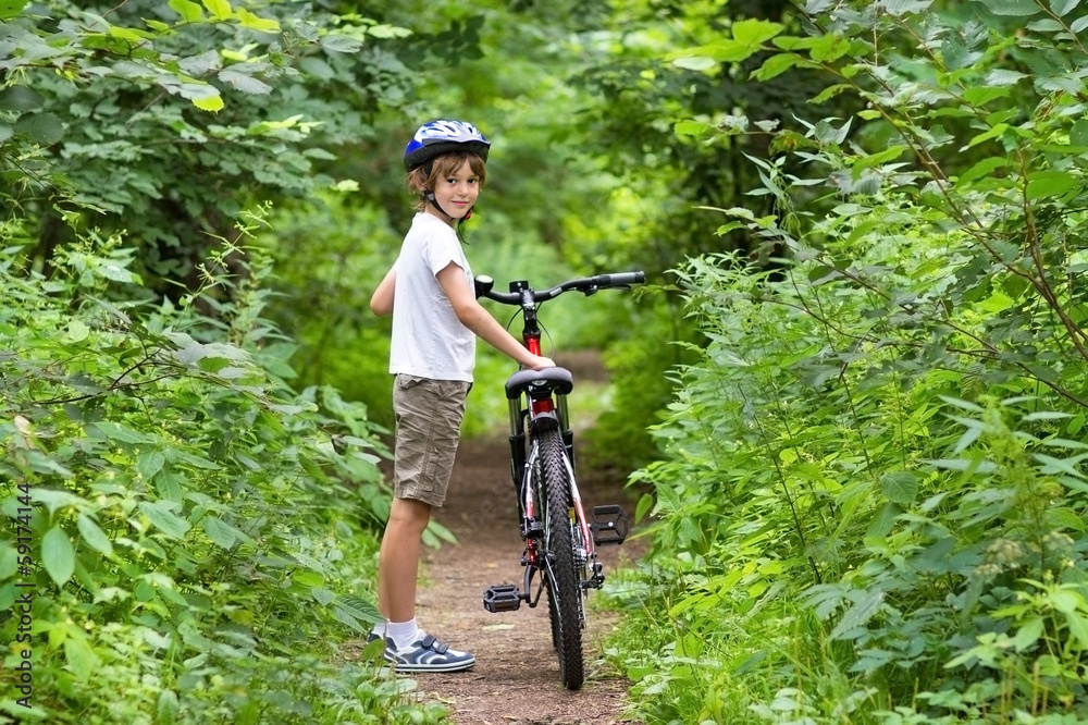 Cute school boy riding a bike in a beautiful summer park Stock Photo ...