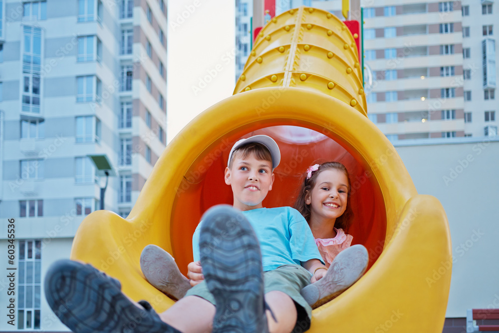 Boy and his younger sister sit at bottom of slide Stock Photo | Adobe Stock