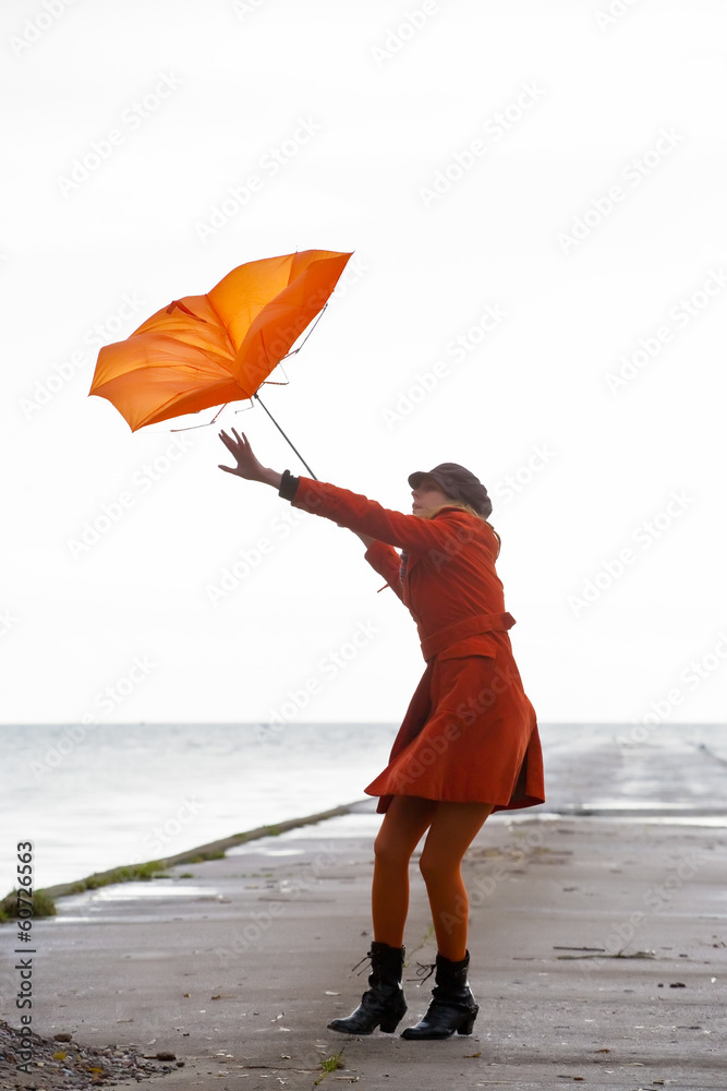 Broken Orange umbrella is flying from the girl. Stock Photo | Adobe Stock