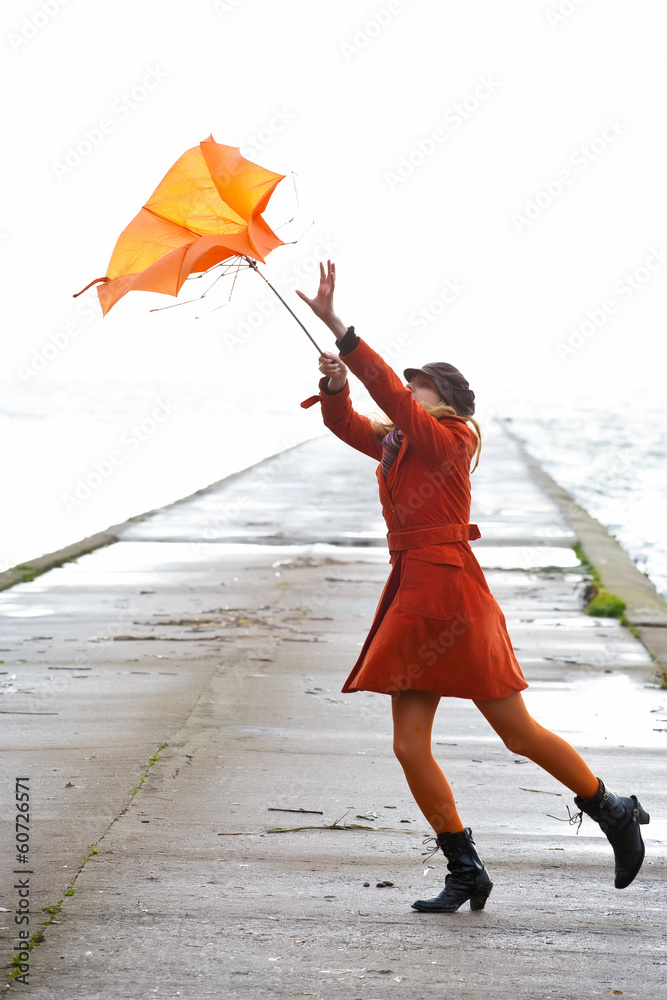 Broken Orange umbrella is flying from the girl. Stock Photo | Adobe Stock
