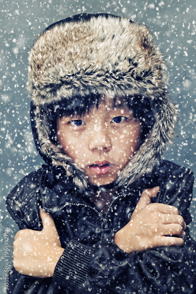 Cute Asian boy freezing in the cold during snowfall Stock Photo | Adobe ...
