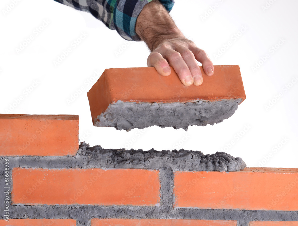 Constructor sujetando un ladrillo construyendo un muro. Stock Photo ...