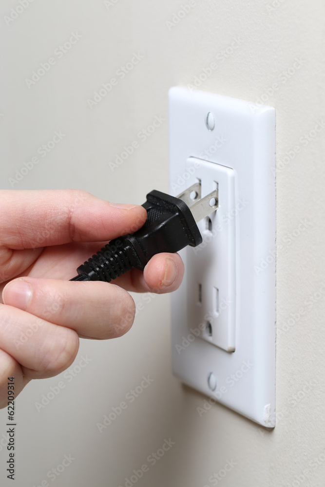 Hand inserting an electrical plug into a wall socket Stock Photo ...