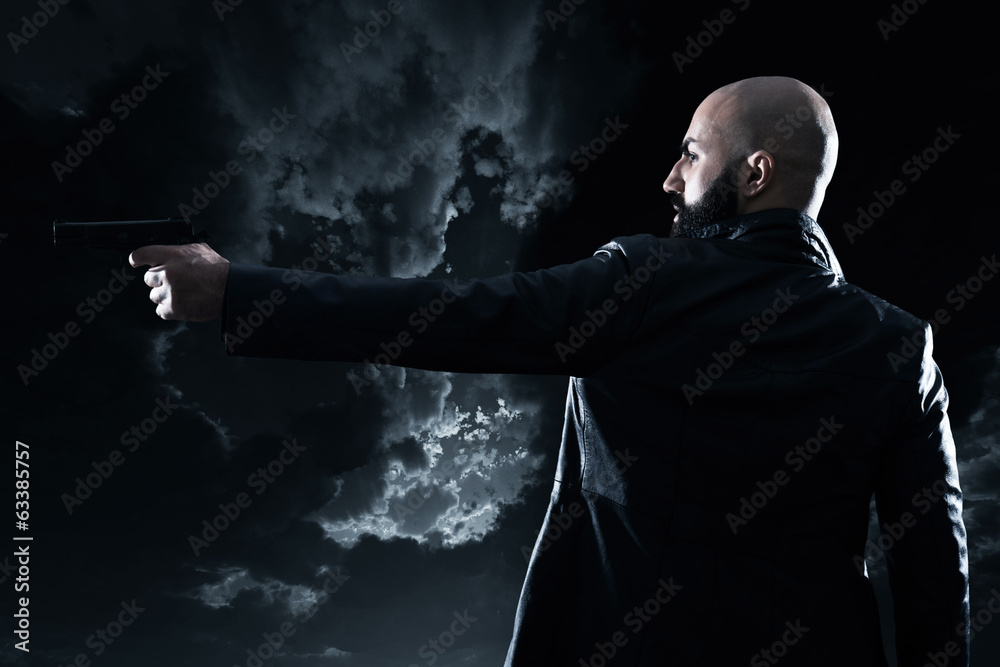 Dangerous bald gangster man with beard holding gun. Wearing blac foto ...