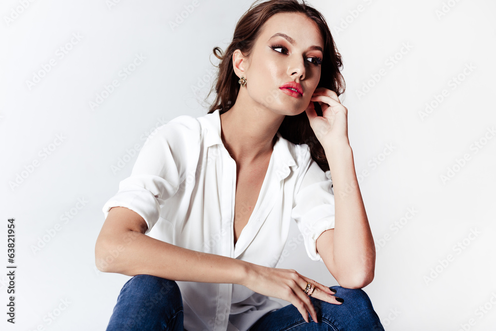 Fashion model sitting on a floor in a blouse and jeans barefoot Stock ...
