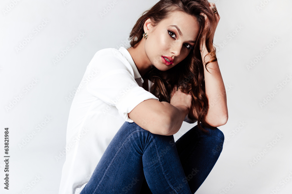 Fashion model sitting on a floor in a blouse and jeans barefoot Stock ...