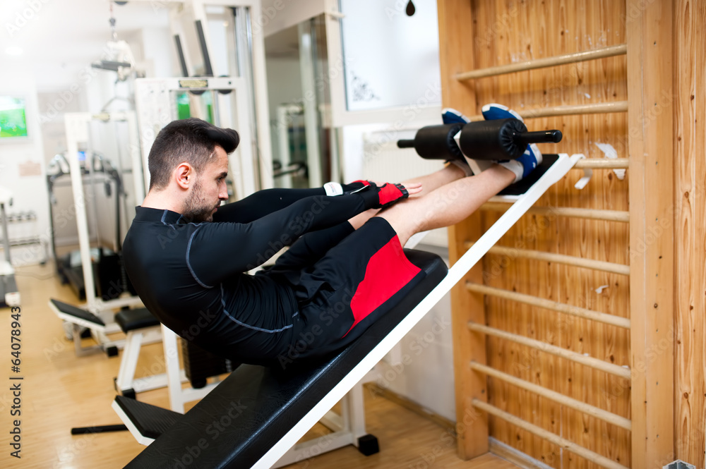 Handsome muscular man doing sit-ups on a incline bench at fitnes Stock ...