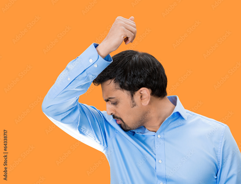 Do I stink? Young man sniffing his armpits on orange background Stock ...