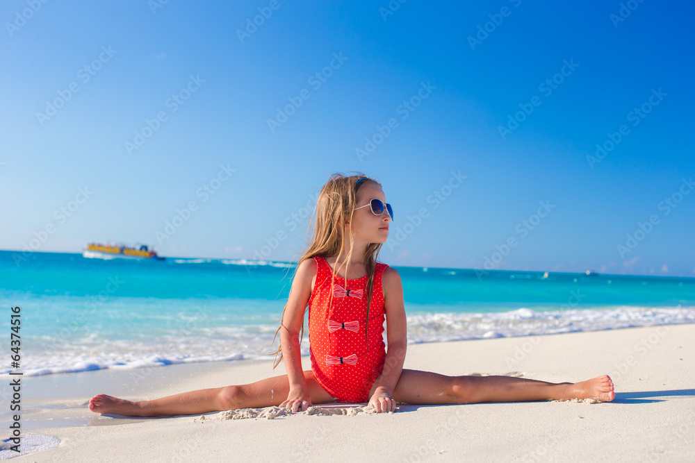 Foto de Little girl sitting on the splits at white sandy beach do Stock ...