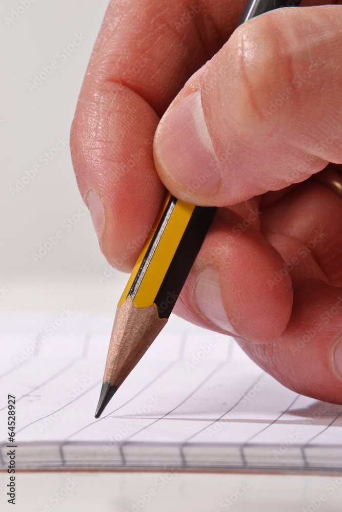 Mano escribiendo con un lápiz en un cuaderno. Stock Photo | Adobe Stock