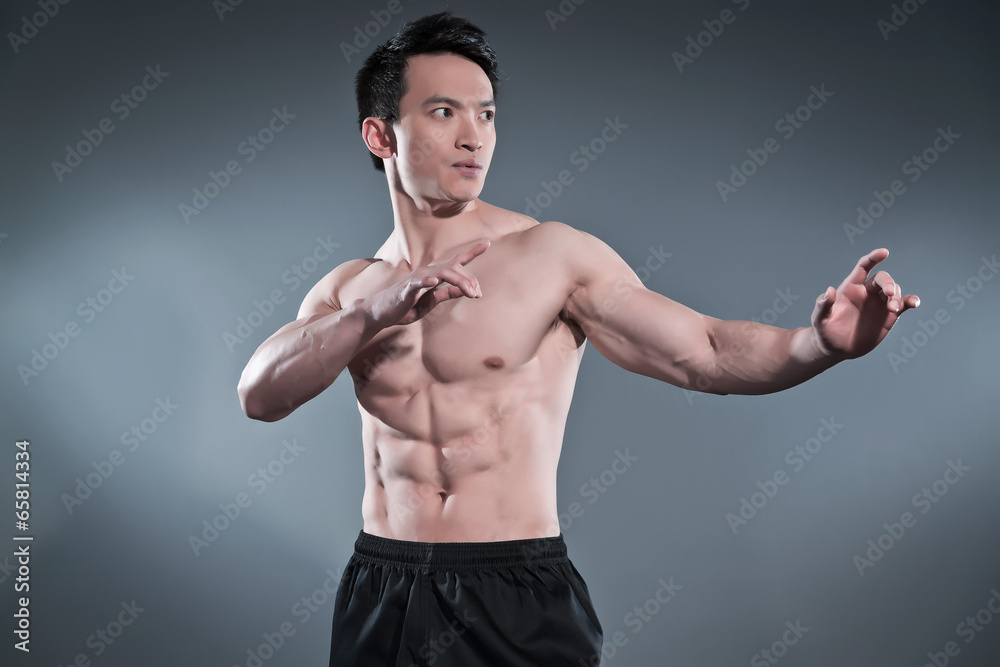 Muscled asian kung fu man in action pose. Wearing black pants. S Stock ...