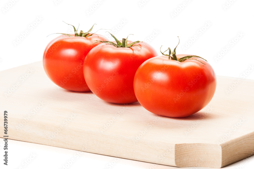 Three tomatoes standing in line on wooden board. Stock Photo | Adobe Stock