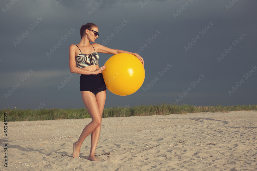 VINTAGE STYLED MODEL POSING WITH BIG YELLOW BALL AT THE BEACH Stock Photo | Adobe Stock