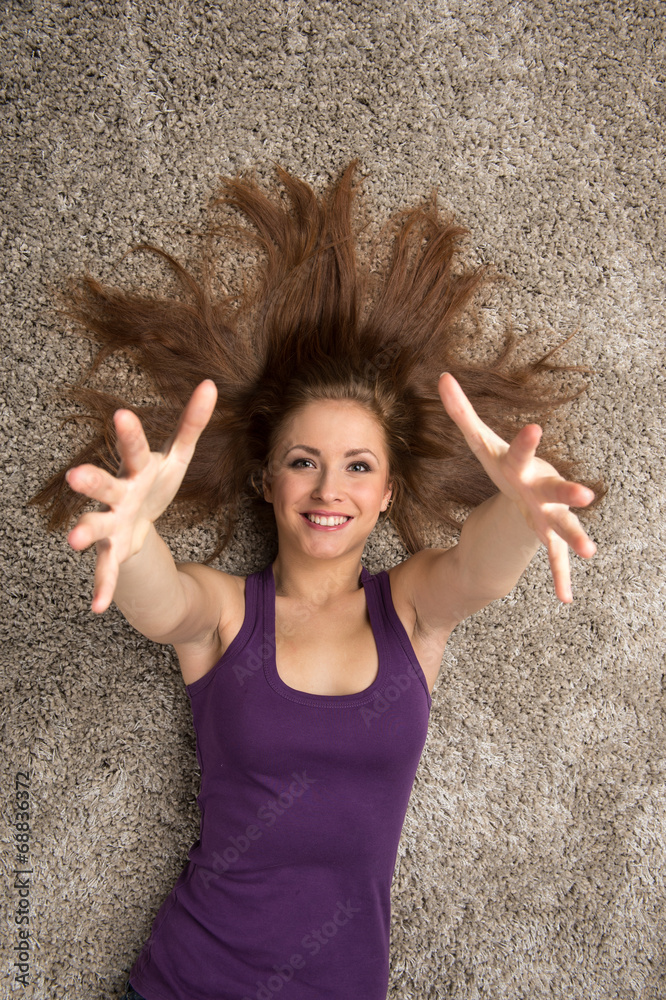 Relaxed woman lying on floor indoors and holding hands up. Stock Photo ...