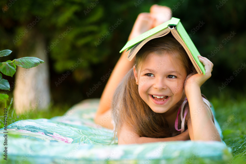 Little girl is hiding under book outdoors Stock Photo | Adobe Stock