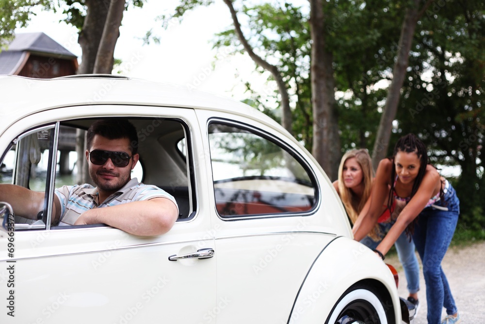junge Frauen schieben ein Auto an Stock-Foto | Adobe Stock